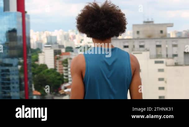 Young black african man overlooking city view on top of rooftop ...