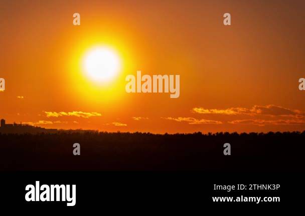 Time lapse bright orange sunset sun sets behind the clouds. The end of ...