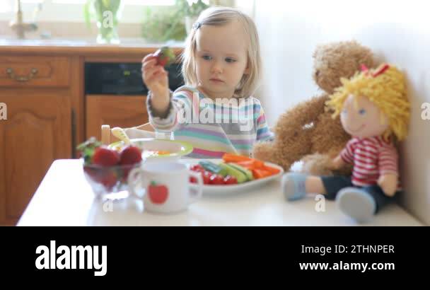 Adorable toddler girl eating fresh fruits and vegetables for lunch ...