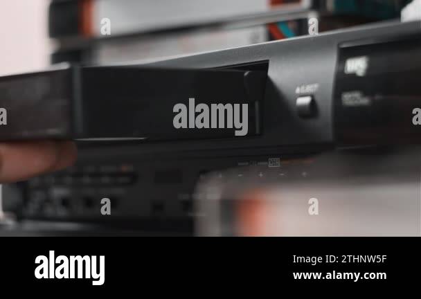 Male hand inserts VHS cassette into a VCR Video recorder. Black vintage ...