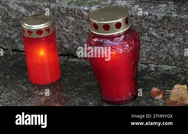 Row red memorial candle burning with fire on rainy day on tombstone in ...