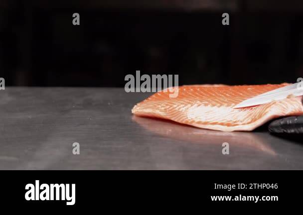 Close-up of chef hands preparing a fresh salmon on a cutting table ...