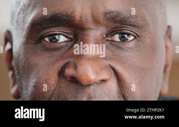 Extreme close-up male wrinkled face with dark skin eyes looking at ...