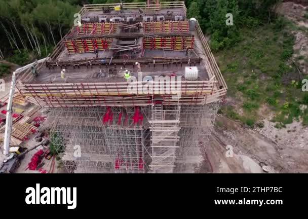 Construction of concrete overpass bridge with red pillars and metal ...
