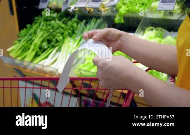 A woman checks a paper check after shopping for groceries at the mall ...