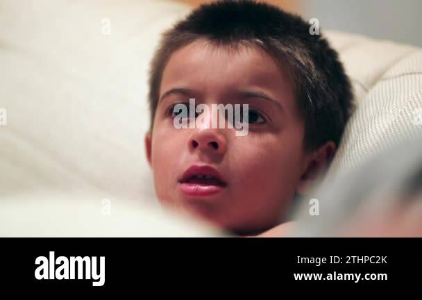 Young boy hypnotized by TV screen seated at home sofa at night Stock ...