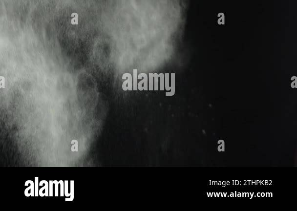 Throwing flour on a black background. White dust explosion effect. For ...