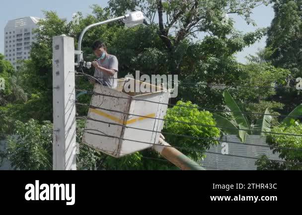 Worker on height lifting platform installing new street light bulb ...