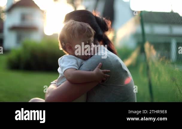 Mother embracing baby outside during sunset. Parent consoling hugging ...