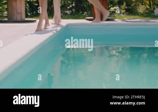 Women in bikini are walking on the edge of a swimming pool with ...