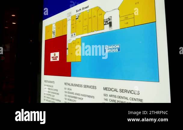 Woman checking store position in front of directory sign inside ...