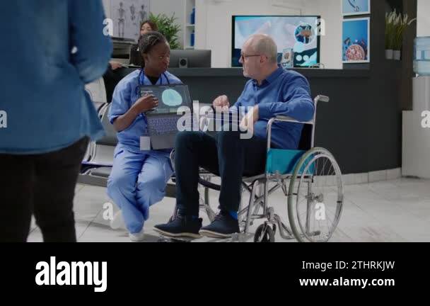 Nurse showing human brain neural system to wheelchair user at medical ...