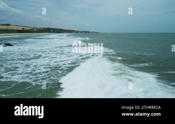 Aerial view footage taken by drone of ocean blue waves crashing against ...