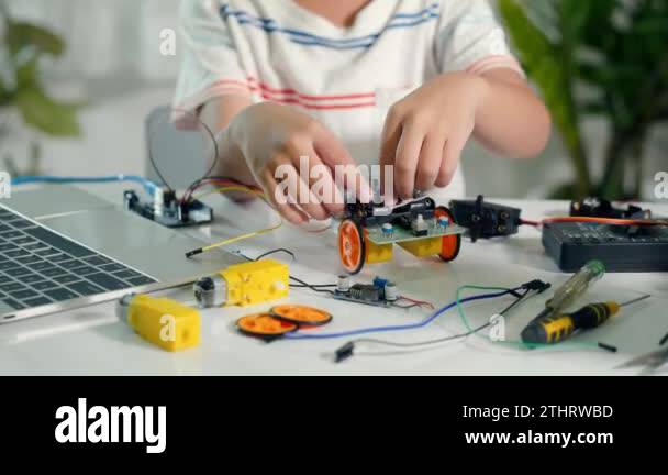 Asian kid boy assembling board into Arduino robot car homework, Little child assemble DC to DC ...
