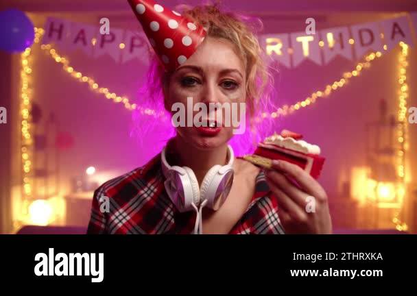 Crying woman in a party cap with smeared lipstick eating cake with ...