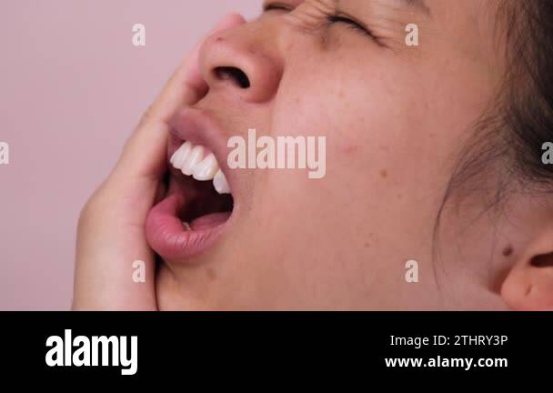 Close-up of woman having toothache and her hands touching her face ...