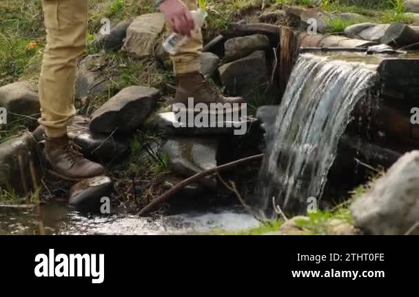 man drinking water from stream with her hands. male hands draw water ...