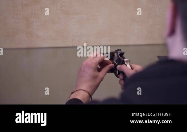 Rear view of a man puts a bullet in a gun puts a gun to his head and is ...