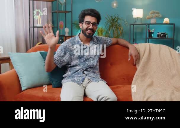 Hello. Indian handsome man smiling friendly at camera and waving hands ...