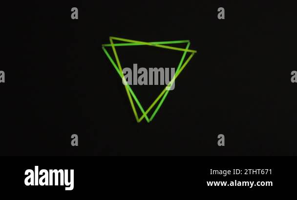 Animation of green neon glow sticks forming triangles over black background with copy space ...