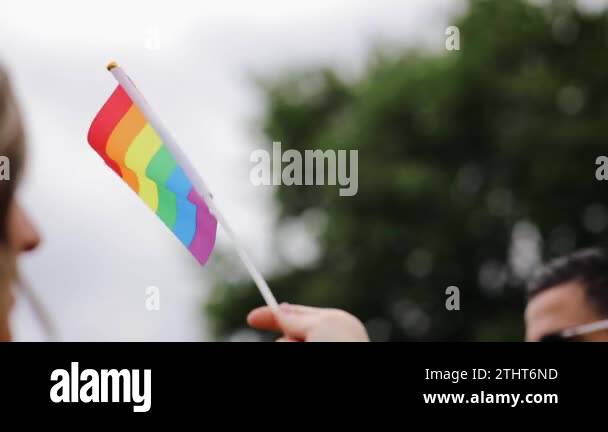 Unrecognisable woman holds and waving rainbow flag on the blurred ...