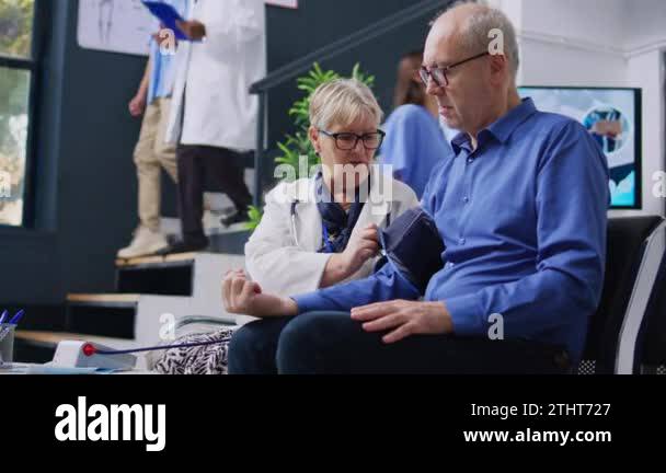 Elderly doctor using tonometer instrument to measure old patient pulse ...