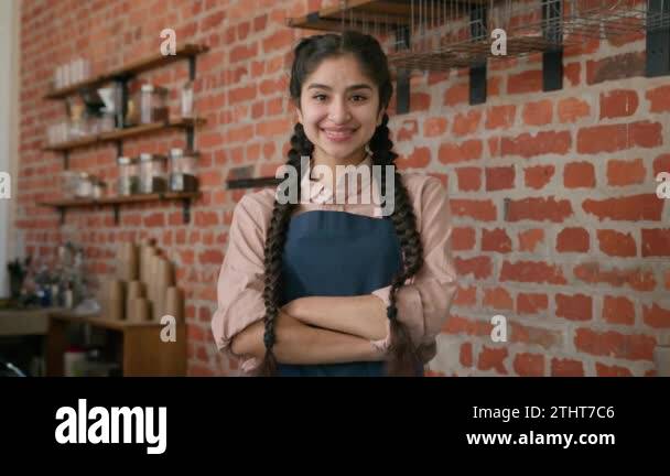 Portrait smiling indian woman waitress barista in apron posing in cafe ...