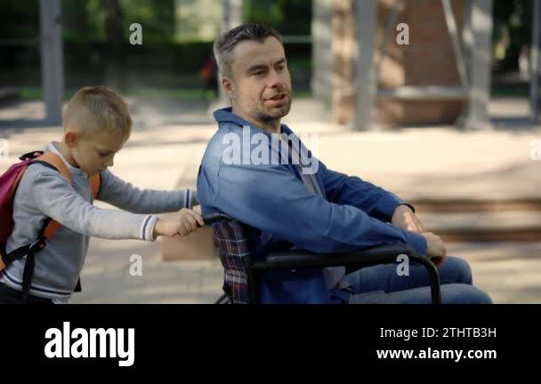 Side view of the son went for a walk with his disabled father and ...