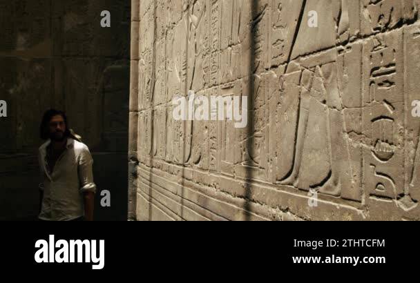 Tourist walking beside an ancient pharaonic wall full of hieroglyphic ...