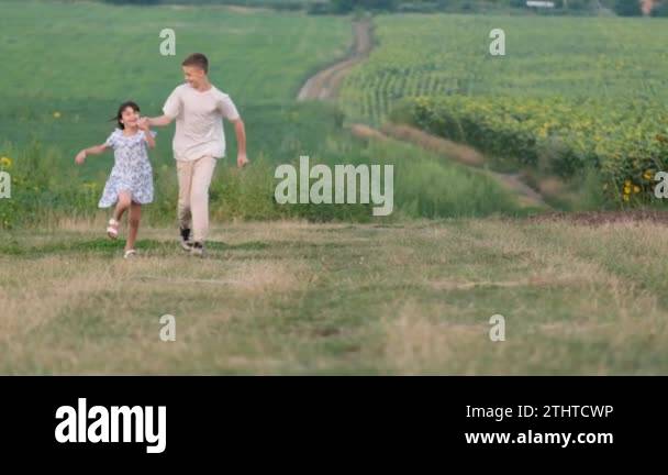 Happy children. A little girl and a teenage boy are running across a ...