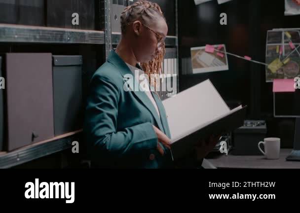 Police investigator reading case file in evidence room filled with ...