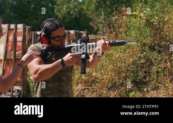 White woman and man wearing safety gear at outdoor shooting range ...