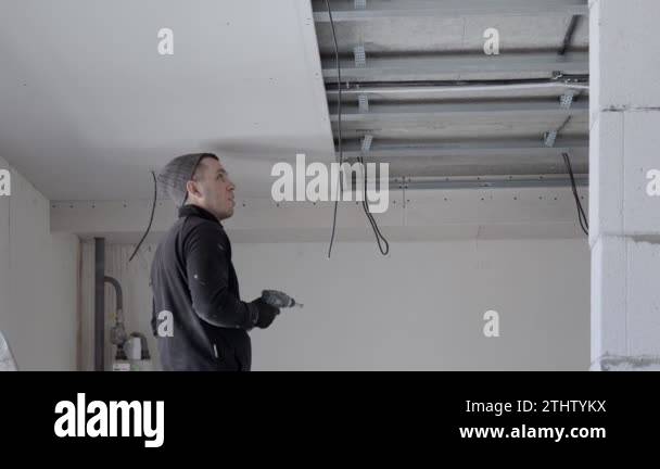 Construction worker assemble a suspended ceiling with drywall and ...