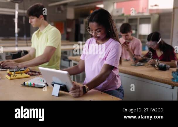 Group of diverse teenage students learning together to build electronic ...