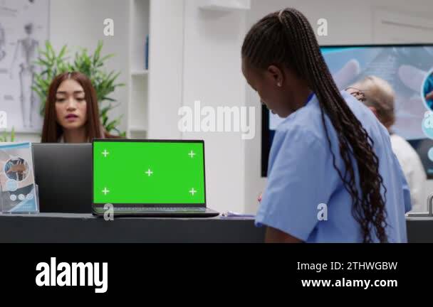 African american nurse using laptop with greenscreen display at ...