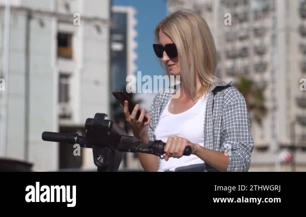 Blonde woman with black glasses uses app on her smartphone to unlock ...