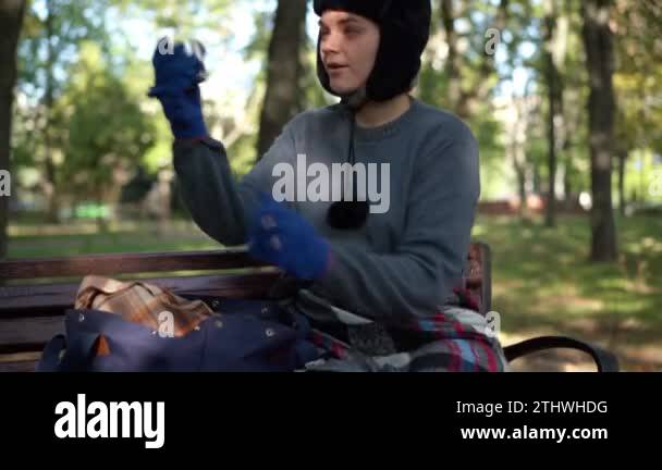 Excited homeless woman kissing food can sitting on bench in sunny park ...