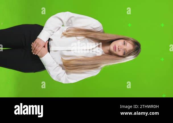 Front view of pretty, young lady standing in studio, holding hands ...