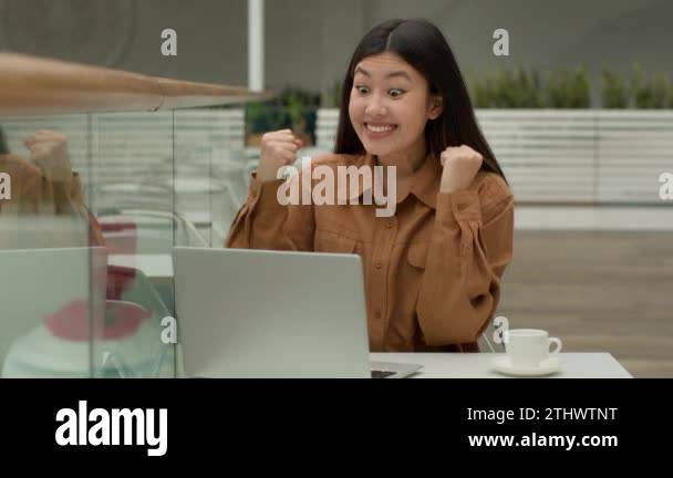 Happy shocked Asian woman businesswoman sit in cafe with laptop ...