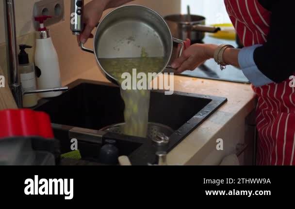 Woman Draining Water Of Boiled Potato Dough Lumps In The Kitchen Sink ...