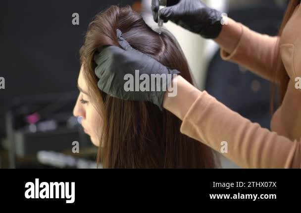 Unrecognizable slim female hairdresser applying moisturizer rubbing ...