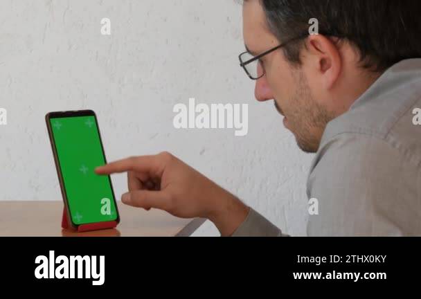 Green screen chroma key on a smartphone, the hands of a man in a shirt ...
