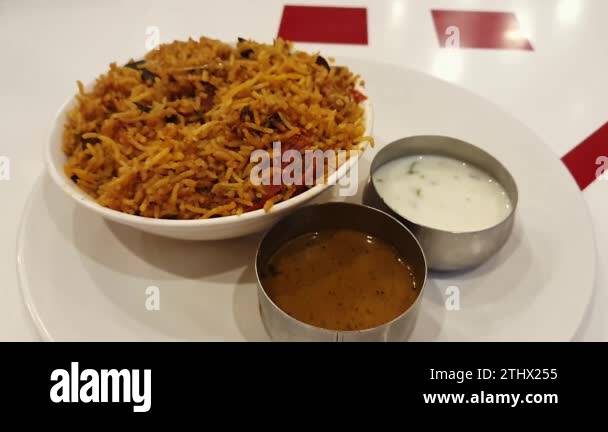 Unique Indian food chicken biriyani served on bowl with curd and curry ...
