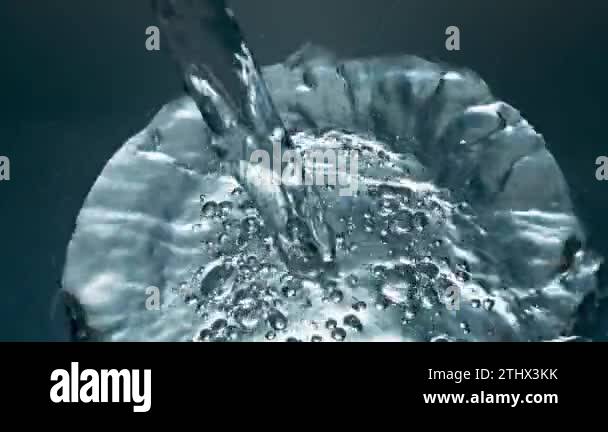 Mineral water pouring transparent glass closeup. Numerous blebs going ...