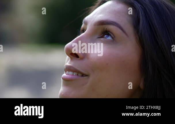 Young woman close up face gazing at sky with faithful expression ...