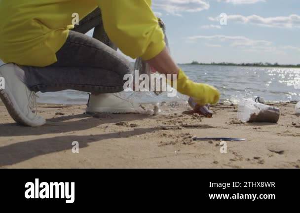 Young woman takes care of environment picking up trash lying on wet ...
