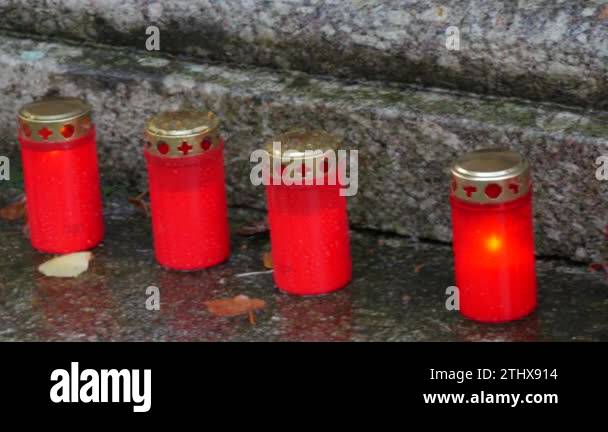Row red memorial candle burning with fire on rainy day on tombstone in ...