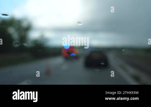 Driving in drizzle past police car with emergency lights flashing ...