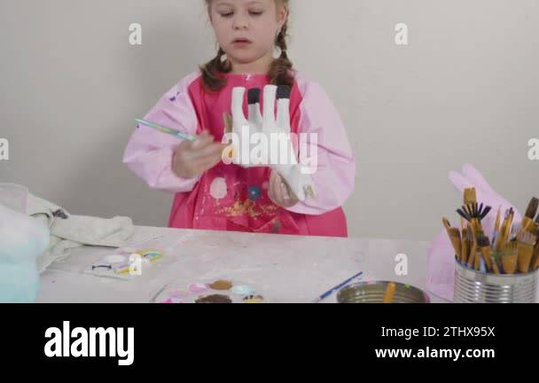 Little girl painting paper mache figurine at homeschooling art class ...