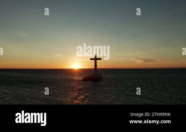 Colorful bright clouds during sunset over the sea. Catholic cross in ...